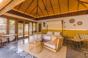 Um quarto amplo com uma cama grande, um sofá, um espaço de refeições e um ventilador de teto.