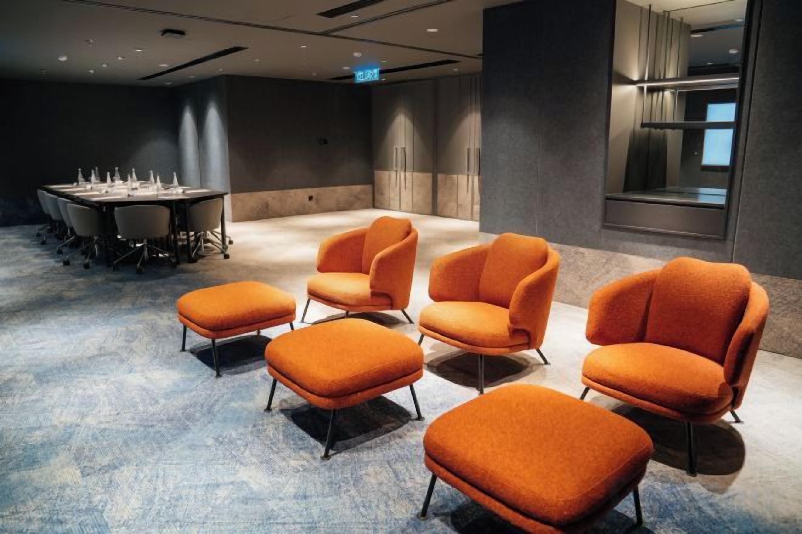 Uma sala de conferências com uma mesa redonda e seis cadeiras laranja.