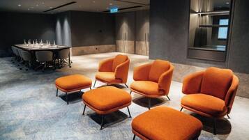 Uma sala de conferências com uma mesa redonda e seis cadeiras laranja.