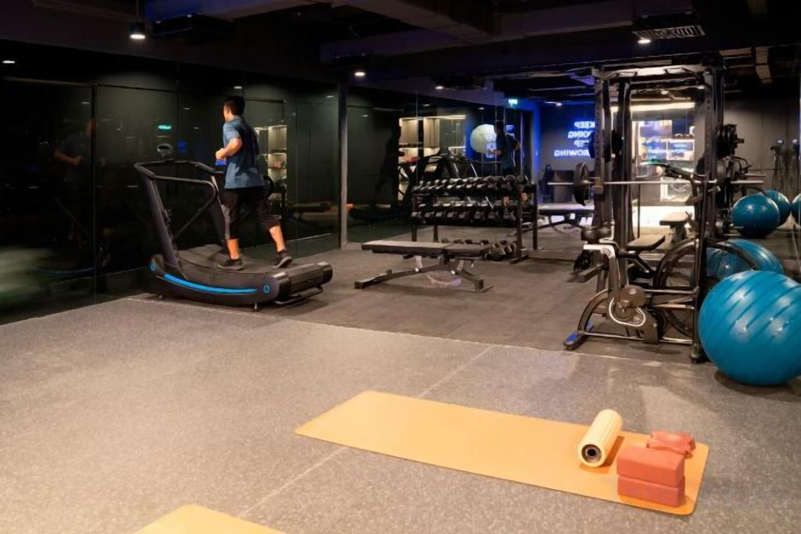 Academia com esteira, aparelhos de musculação e bolas de exercício.