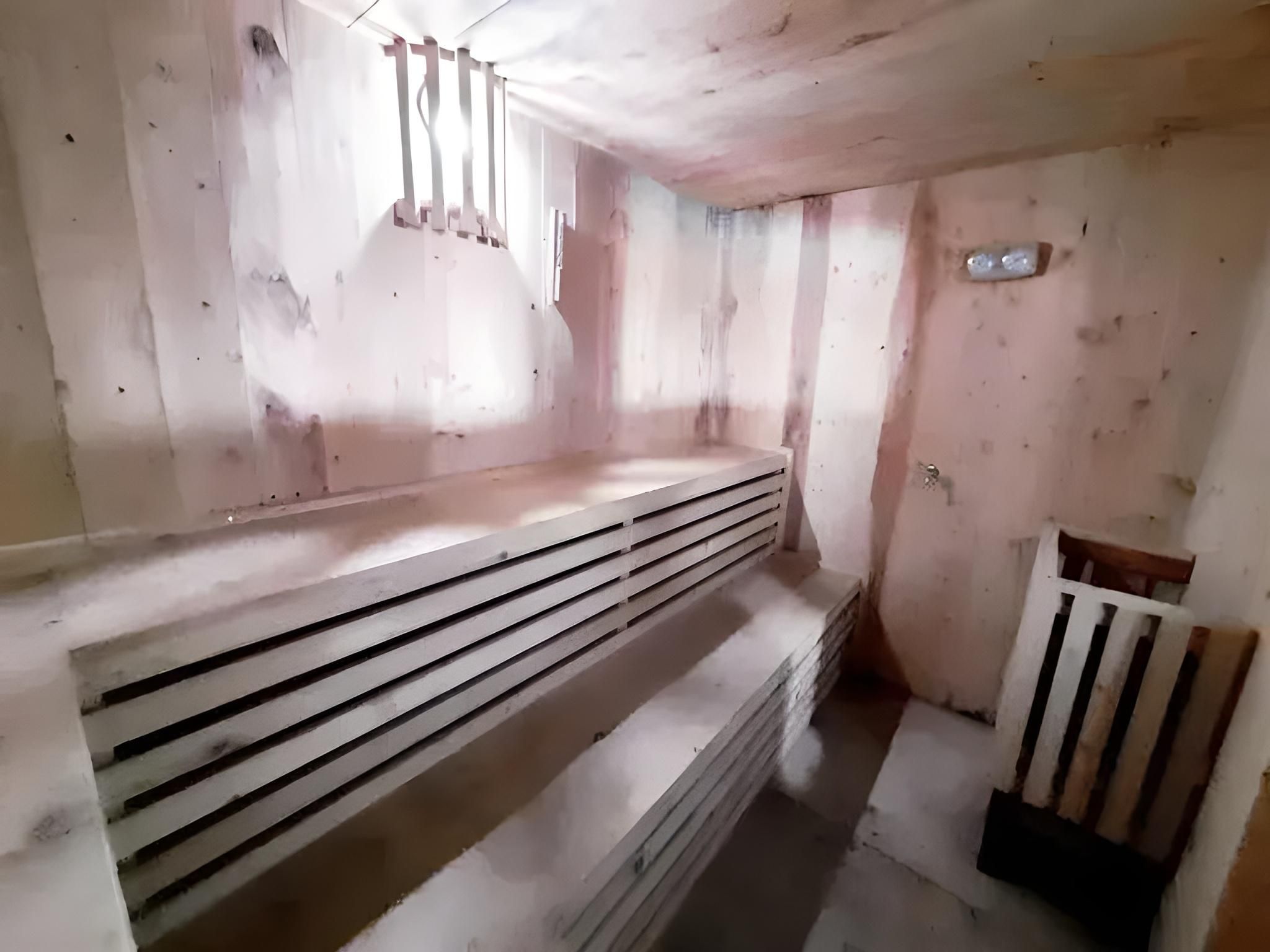 Quarto com um banco de madeira, um radiador e uma pequena mesa.