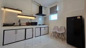 Uma cozinha moderna com armários brancos, um exaustor preto e uma geladeira preta.