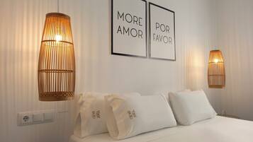 Quarto de hotel com uma cama, duas luminárias fixadas na parede e dois quadros com texto.