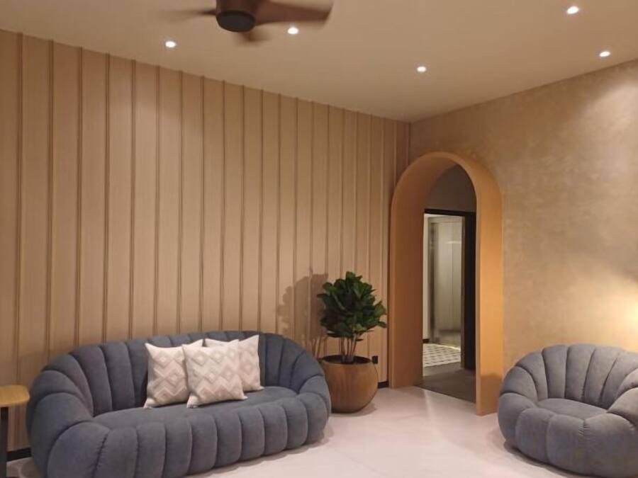 Uma sala de estar moderna com um sofá, uma poltrona redonda, uma planta em vaso e um ventilador de teto.