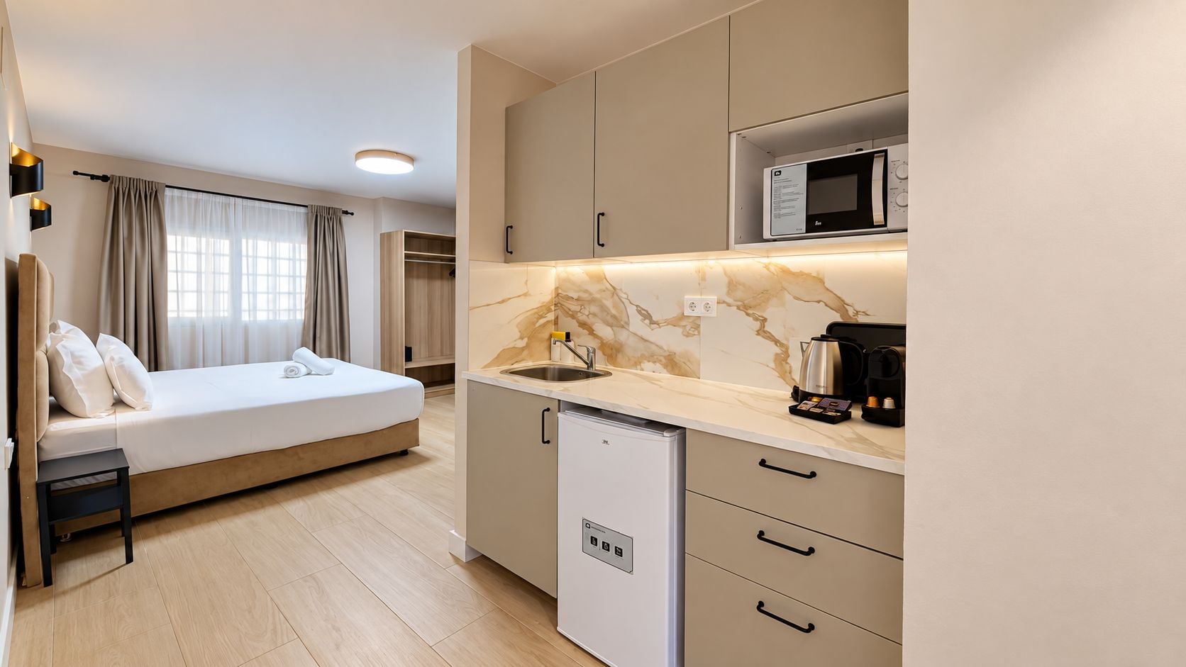 Quarto de hotel compacto com cama, cozinha compacta e banheiro pequeno.