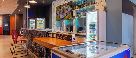 Uma área de bar moderna com balcão, banquetas e uma máquina de sorvete grande.