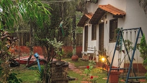 Um jardim com um caminho de pedra, baloiço e uma casa com telhado de telhas.