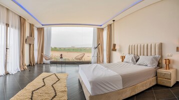 Quarto com uma cama grande, uma escrivaninha e uma cadeira, com vista para a paisagem pela janela.