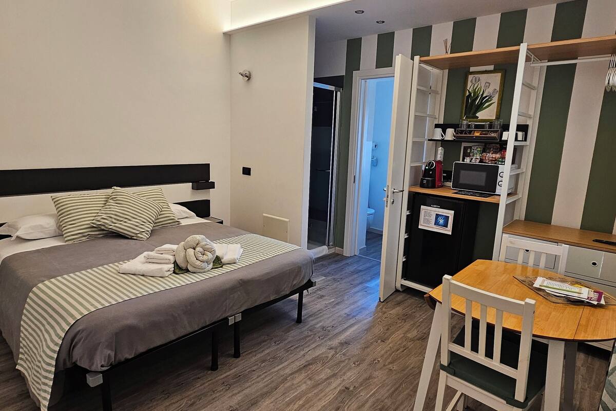 Quarto com cama, mesa de cabeceira e escrivaninha com cadeira.