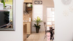 Uma sala de estar moderna com um sofá cinza, uma televisão e uma área de jantar com mesa e cadeiras.