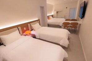 Quarto de hotel com duas camas, uma escrivaninha e uma cadeira.