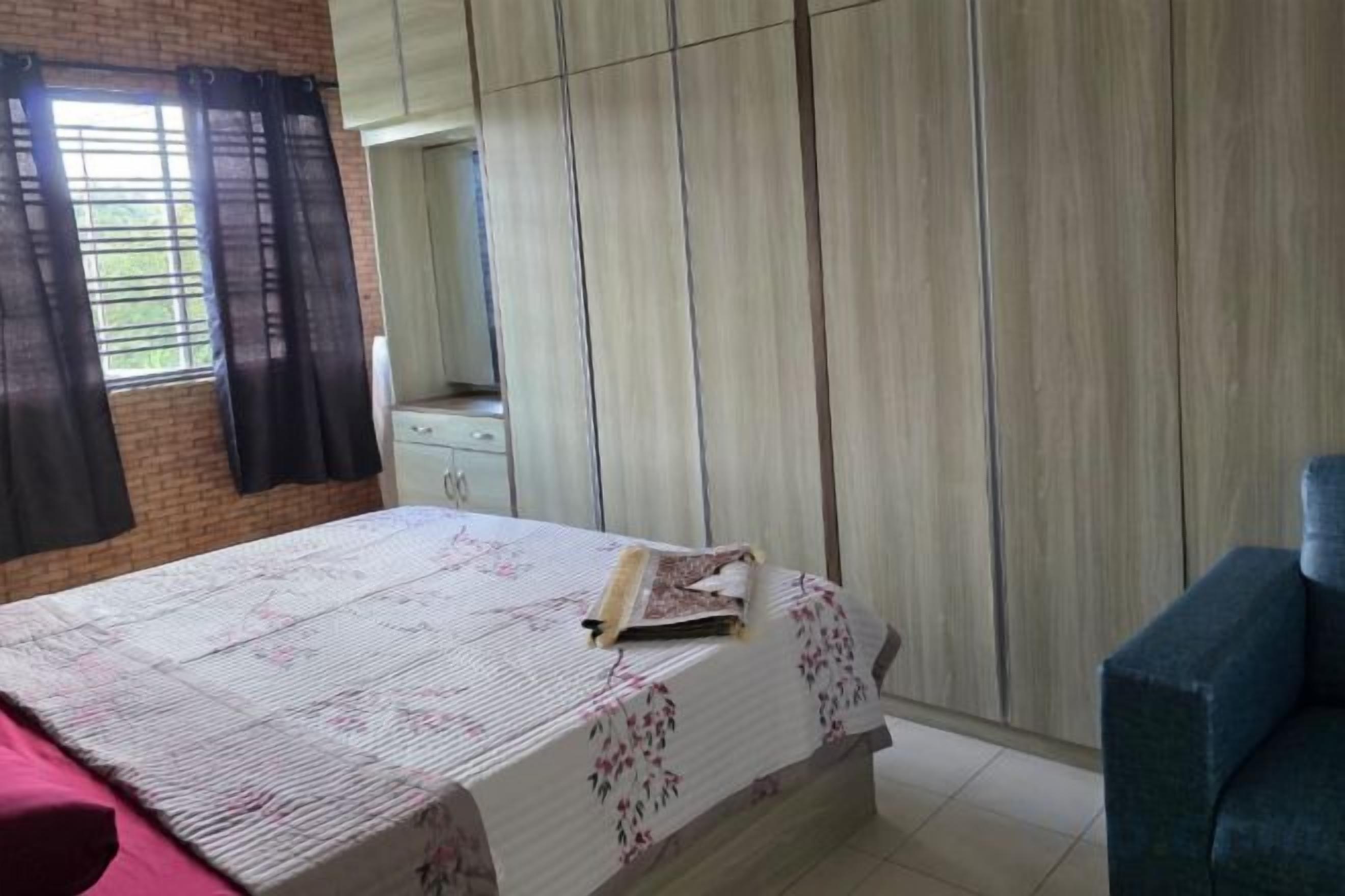 Quarto com cama, cômoda e janela com cortinas.