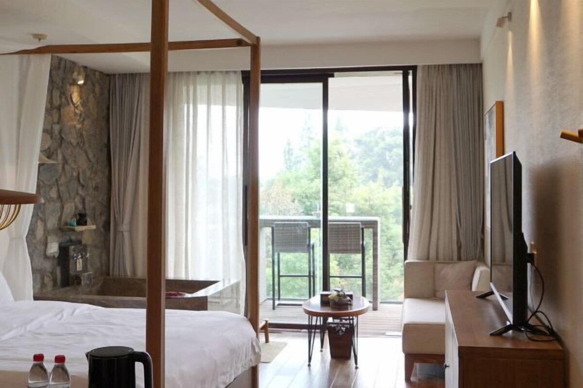 Quarto com cama de dossel, varanda com mesa e cadeiras, e uma televisão sobre uma mesinha de madeira.