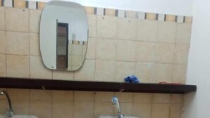 Casa de banho com duas pias, um espelho e parede revestida a azulejos.