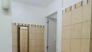 Casa de banho com espelho, paredes em azulejo e porta que dá para outro espaço.