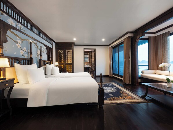 Quarto de hotel espaçoso com uma cama grande, área de estar com vista e um painel decorativo.