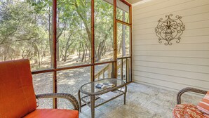 Um quarto com janelas amplas, móveis de vime e um objeto decorativo na parede.