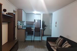 Um espaço compacto para viver, com cozinha americana, área de jantar e sala de estar.