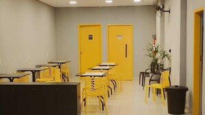 Um quarto amplo com cadeiras e mesas amarelas, uma mesa de recepção e duas portas.