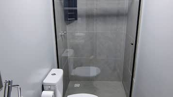 Casa de banho moderna com cabine de duche em vidro, lavatório branco e sanita.