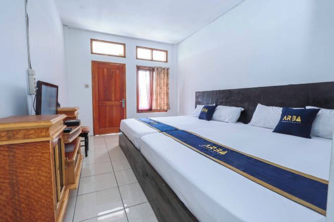 Quarto de hotel com uma cama, uma escrivaninha e uma porta.