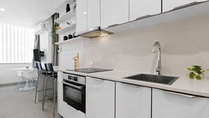 Uma cozinha moderna com armários brancos, uma pia de aço inoxidável e um forno embutido.