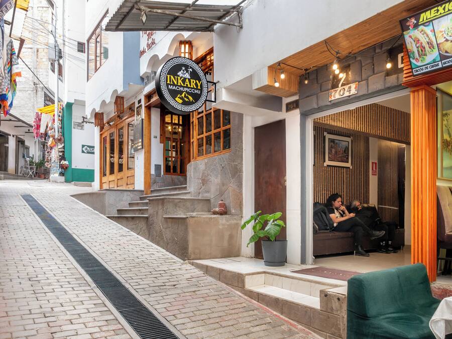 Uma rua estreita com um restaurante chamado "INKARY MACHUPICCHU" e uma placa indicando comida "MEXICANA".