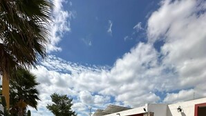 Um edifício com área externa coberta, calçada pavimentada e cavalos.