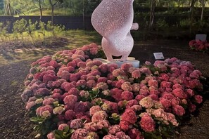 Um jardim com uma escultura cercada por diversas flores.