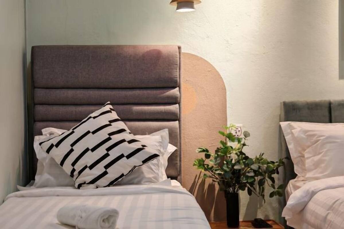 Quarto com uma cabeceira grande, mesa de cabeceira com uma planta e cama bem arrumada.