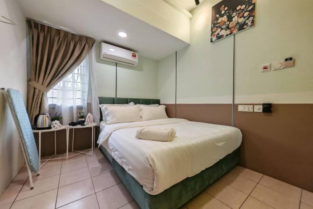 Quarto com cama, mesa de cabeceira, ar condicionado, janela com cortinas e uma obra de arte pendurada na parede.