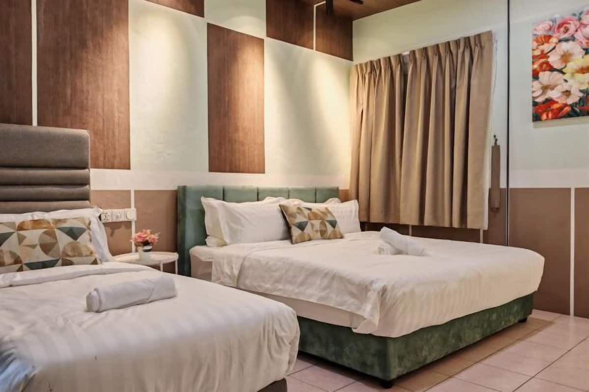 Quarto de hotel com duas camas, cabeceira verde, parede com padrões geométricos e pintura de flores.