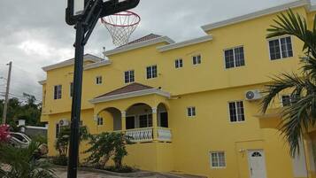 Edifício amarelo com um aro de basquete na frente.