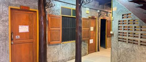 Um corredor com portas de madeira, uma placa de check-out e uma escada com grades de metal.