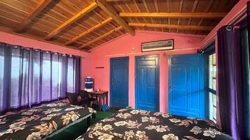 Quarto com duas camas, uma escrivaninha e três portas azuis.
