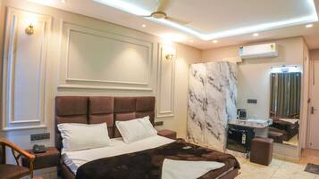 Quarto com uma cama grande, parede decorada em mármore, penteadeira com espelho e ventoinha de teto.