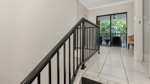 Um interior moderno com escada, vista para o verde através de portas de vidro e um espaço de estar.