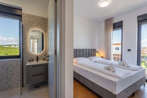 Quarto com cama, mesa de cabeceira, espelho e janela com vista.