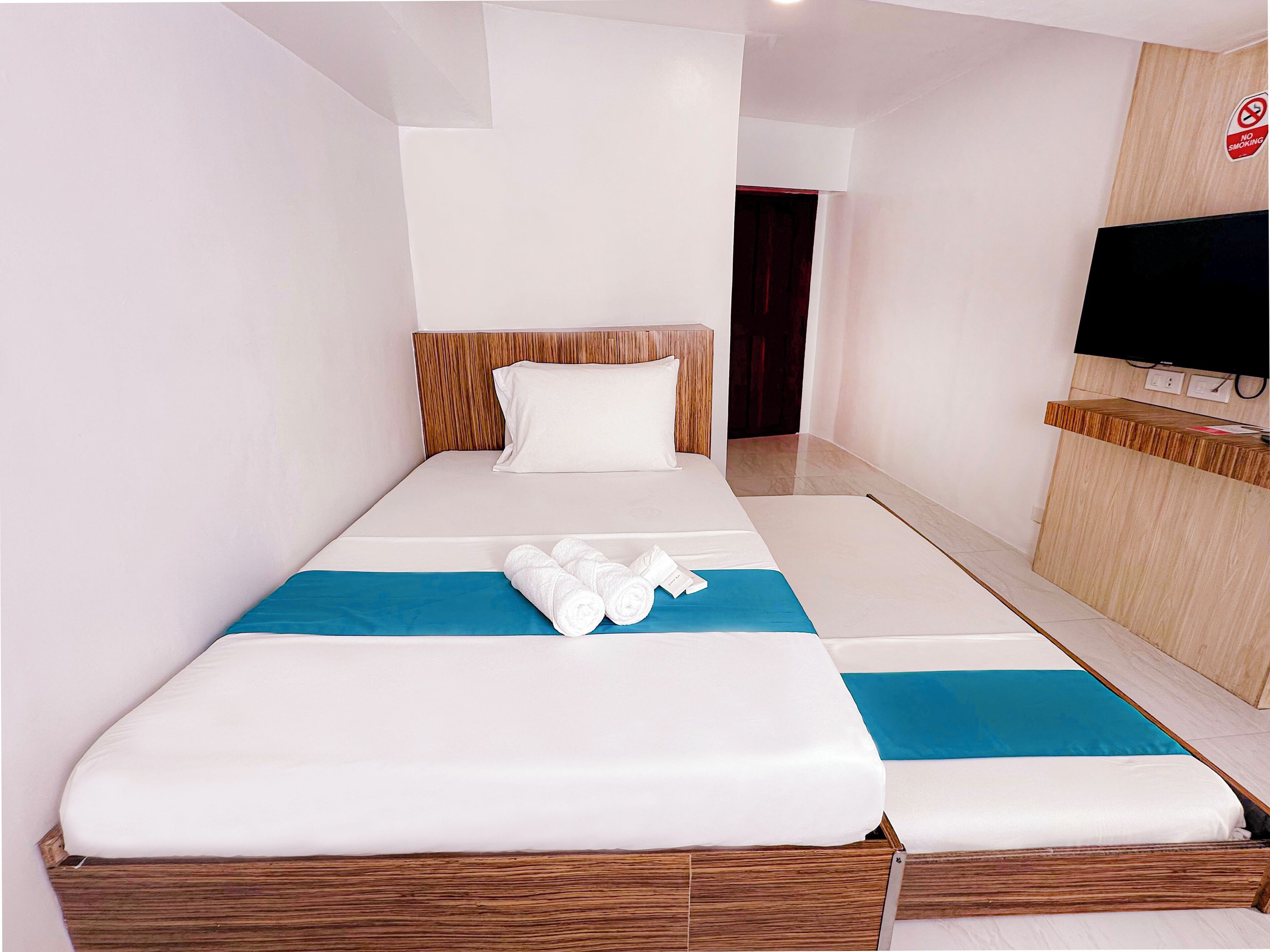 Quarto de hotel com uma cama, televisão e cabeceira de madeira.