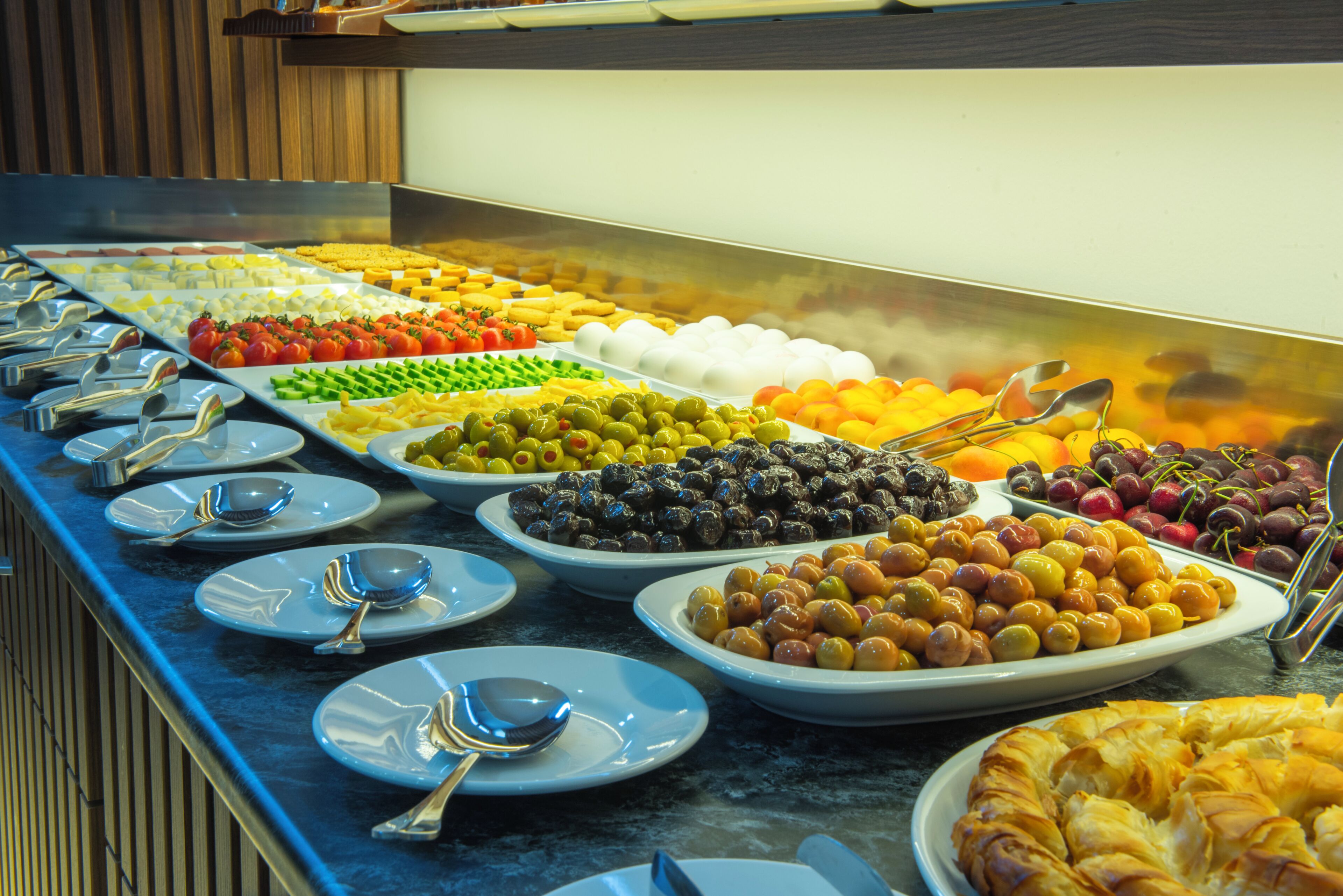 Buffet com diversos alimentos e utensílios.