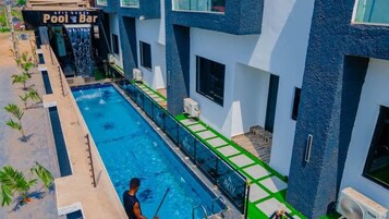Piscina ao lado de um edifício com uma placa que diz 'Pool Bar'.