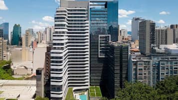 Um edifício alto com design arquitetônico moderno, apresentando fachada curva e várias varandas.
