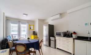 Um espaço compacto com área de jantar, cozinha compacta e pequena sala de estar com sofá e cadeiras.