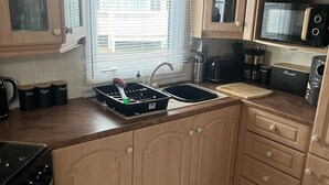 Uma cozinha com armários de madeira, pia, micro-ondas e torradeira.