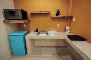 Cozinha compacta com pia, micro-ondas e cafeteira.