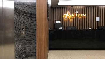 Uma receção com um letreiro de néon, painel de parede de madeira e porta de elevador metálica.