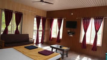 Quarto com cama, sofá, mesa e cortinas.