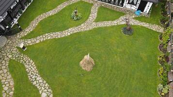 Um jardim ajardinado com um caminho de pedra, uma pequena árvore e um edifício com telhado preto.