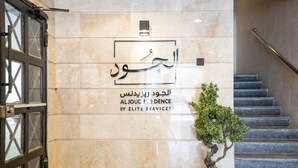 Parede de mármore com escrita árabe e texto em inglês para Aljouad Residence by Elite Services.