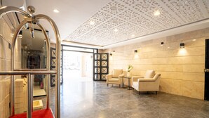 Um hall moderno com piso de mármore, tapete vermelho e dois poltronas bege.